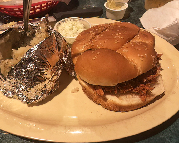 A BBQ sandwich that doesn't need fancy packaging—just a soft bun to cradle that smoky, tender meat alongside a humble baked potato.