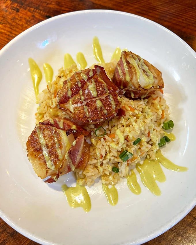These bacon-wrapped scallops aren't just appetizers—they're little flavor bombs of sea-meets-land perfection resting on a bed of seasoned rice.