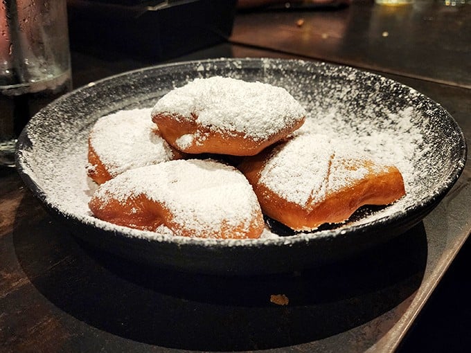 Pillowy beignets under a snowfall of powdered sugar—the only acceptable reason to have white dust on your black shirt.