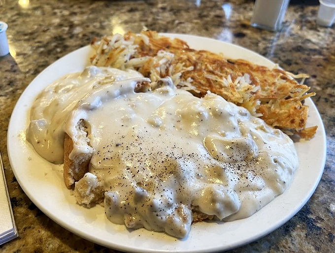 Biscuits and gravy with hash browns—the breakfast trinity that's converted more people than Sunday sermons. A plate of pure American optimism.