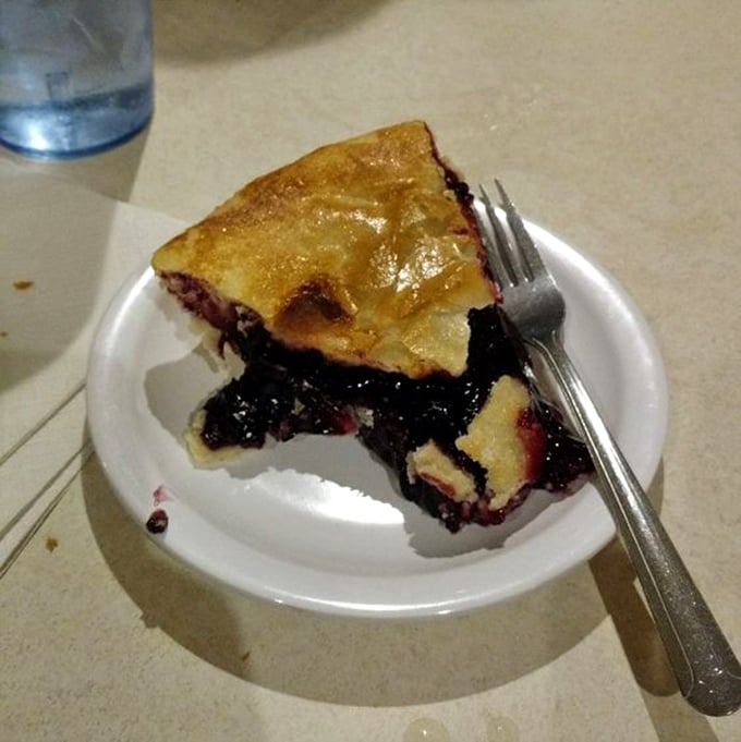This slice of black raspberry pie isn't just dessert—it's a purple-hued time machine to your grandmother's kitchen on a summer afternoon.
