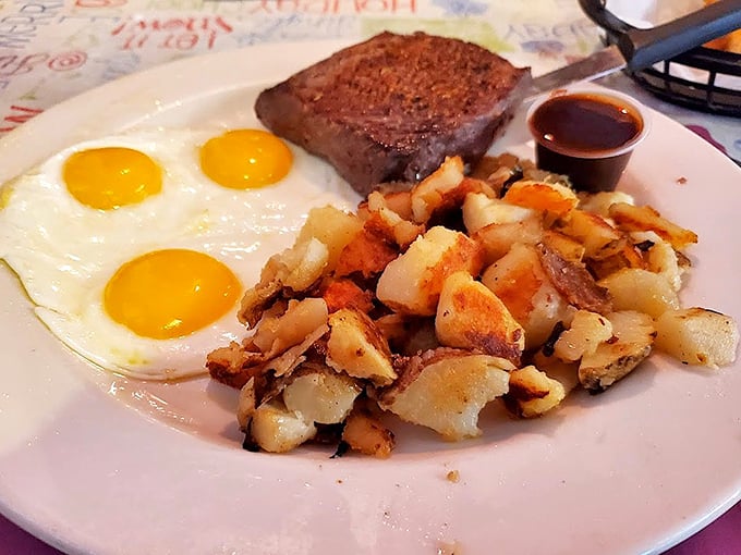 Three sunny-side-up eggs standing guard over perfectly crisped home fries and a steak—breakfast doesn't get more straightforward or satisfying than this.