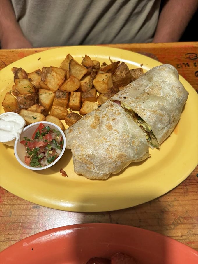 This breakfast burrito isn't messing around—a tortilla-wrapped treasure chest filled with morning delights and served with perfectly seasoned home fries.