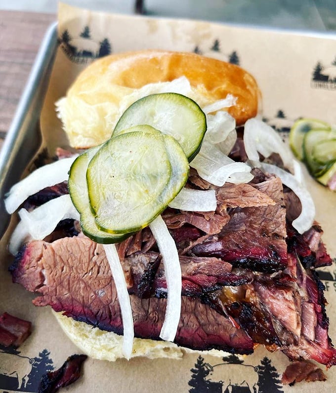 This brisket sandwich is architectural perfection – layers of smoke-kissed beef with pickled cucumber and onion for a perfect balance of rich and bright.