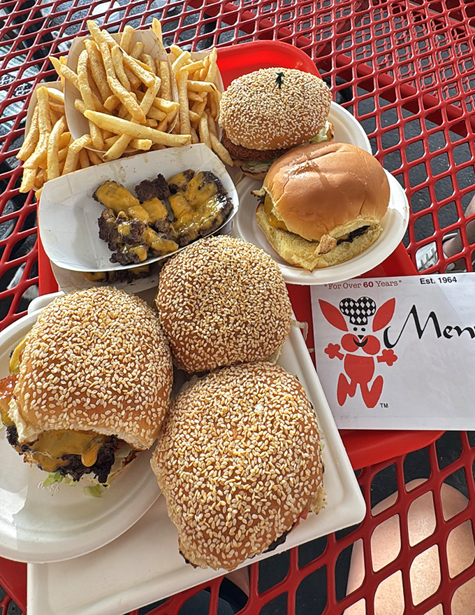 A red picnic table feast that would make any food photographer swoon. These aren't just burgers—they're edible American icons with cheese.