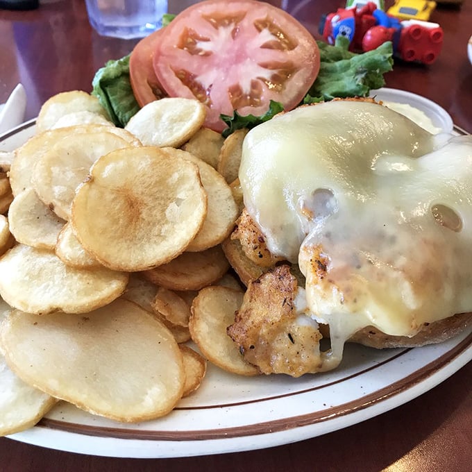 The Cajun Cod Melt sandwich with its golden potato chips isn't just food—it's edible architecture. That melted cheese is making a dramatic entrance.