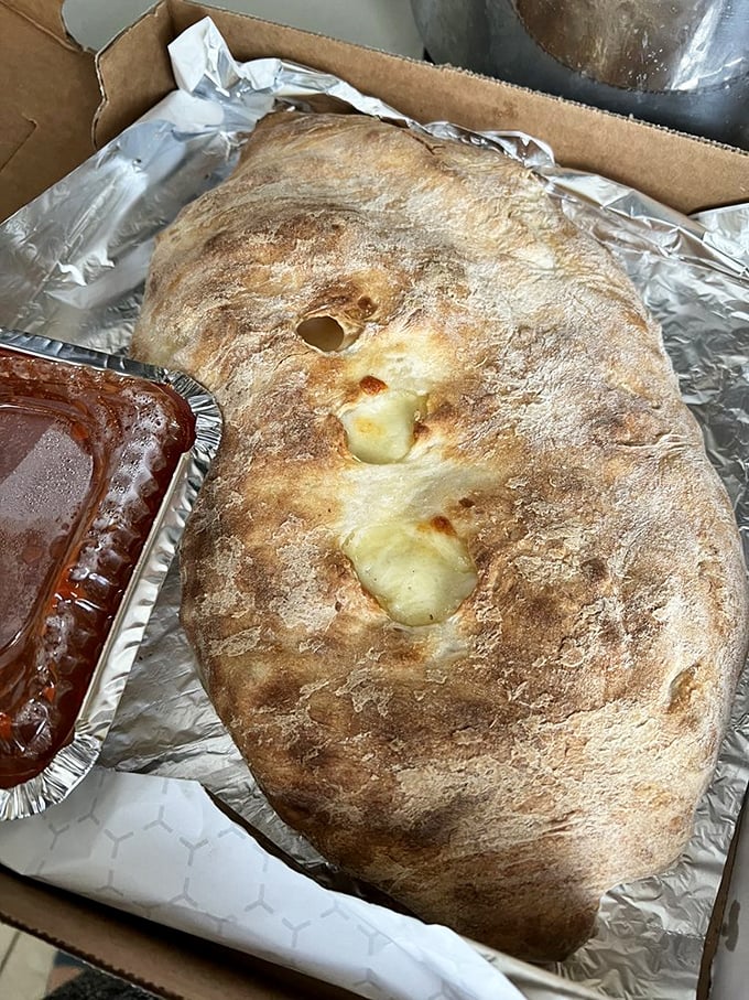 The calzone—pizza's introverted cousin—hides its treasures inside a golden-brown dome that's practically bursting with molten cheese and fillings.