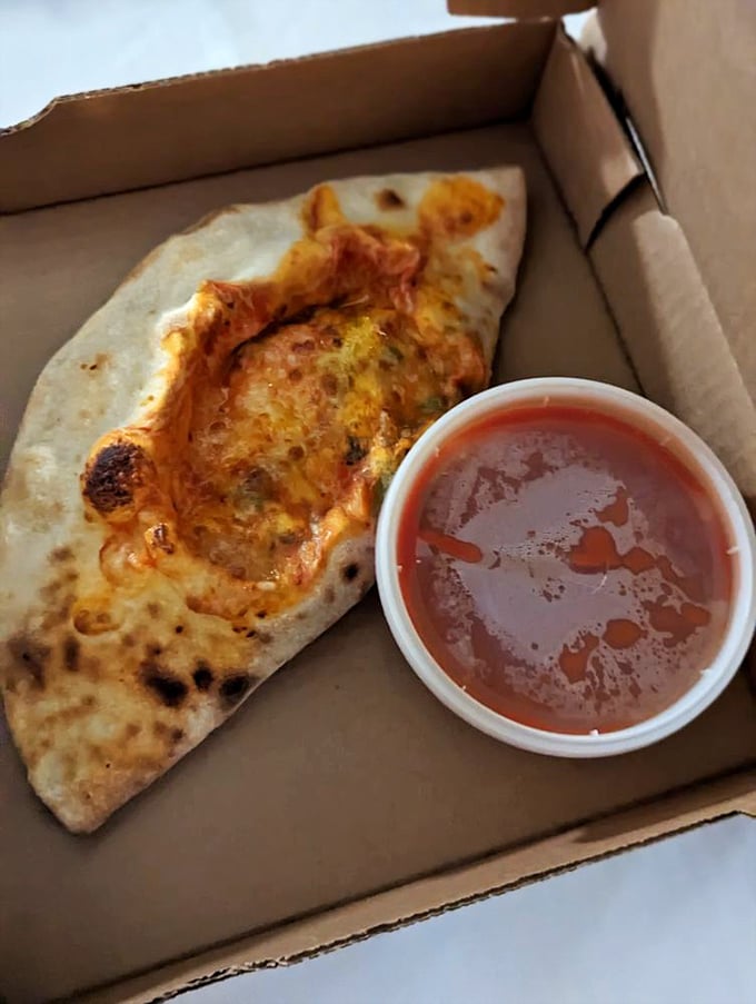 Not quite pizza, not quite sandwich—this calzone with its side of marinara is the culinary equivalent of having your cake and dunking it too.