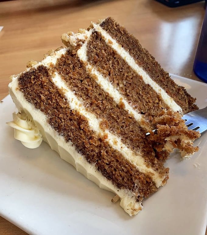 Layer upon layer of moist carrot cake separated by cream cheese frosting—architectural perfection that would make Frank Gehry put down his blueprints and pick up a fork.