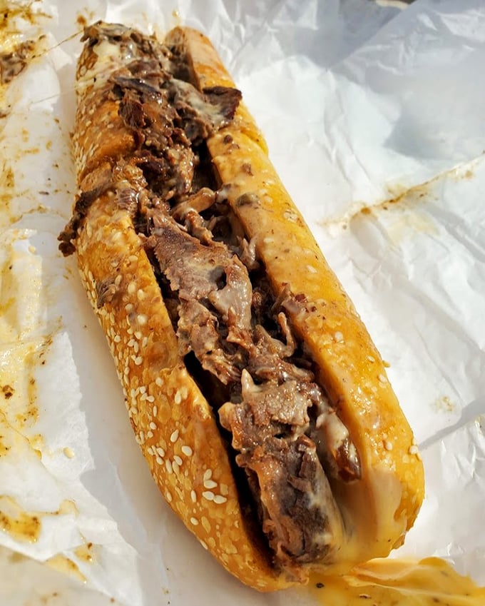 The cheesesteak in its paper wrapping—a beautiful simplicity that reminds us sometimes the best things come in the most unassuming packages.