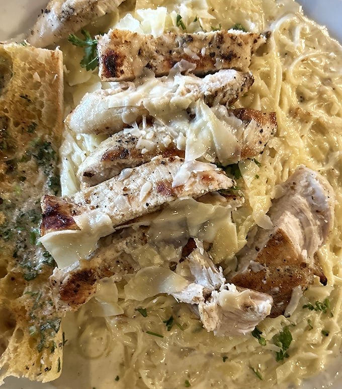 Chicken Alfredo that doesn't hide behind excess – tender slices of chicken resting on pasta bathed in creamy sauce that whispers rather than shouts.