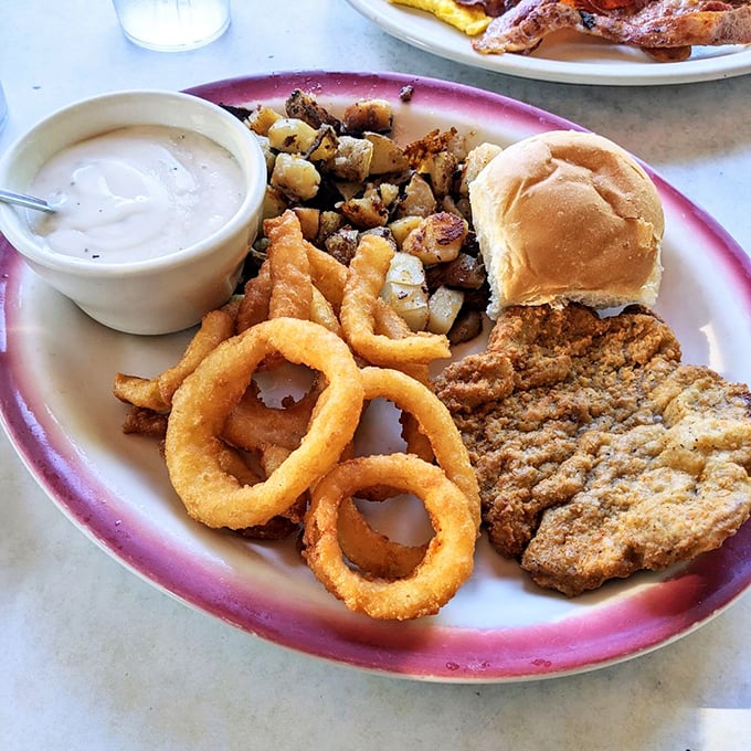 Country fried steak with onion rings—the kind of plate that makes diet books spontaneously combust and nutritionists look the other way. Worth every bite.