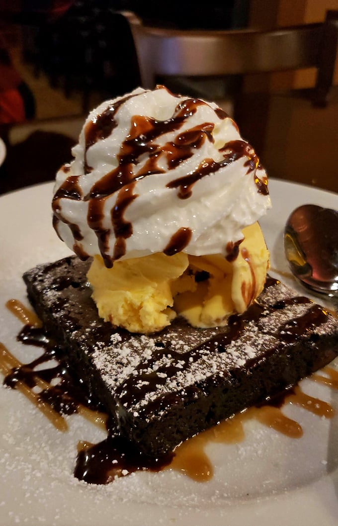 Dessert nirvana achieved: a warm chocolate brownie crowned with ice cream and drizzled with caramel—proof that happiness can indeed be served on a plate.