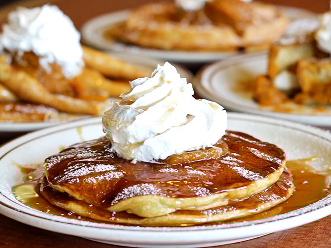 Pancake perfection in its natural habitat. Golden discs of joy topped with a crown of whipped cream and swimming in syrup—breakfast royalty if ever there was such a thing.