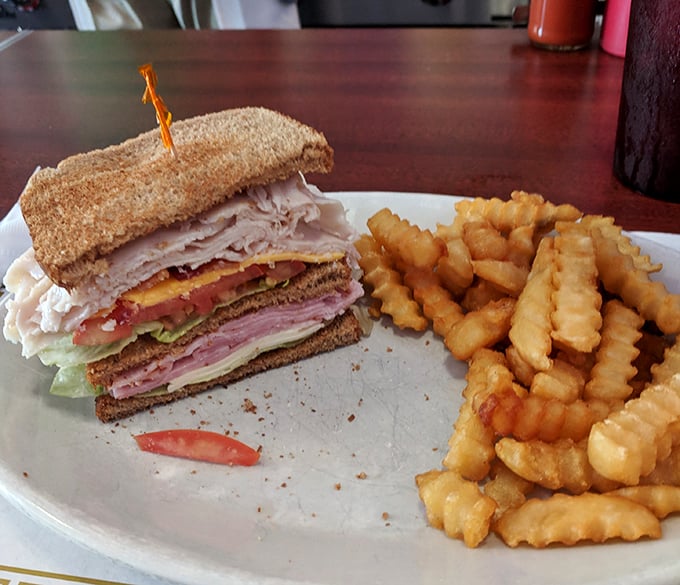 The club sandwich stands tall and proud, layers of deli goodness flanked by an honor guard of golden crinkle-cut fries.