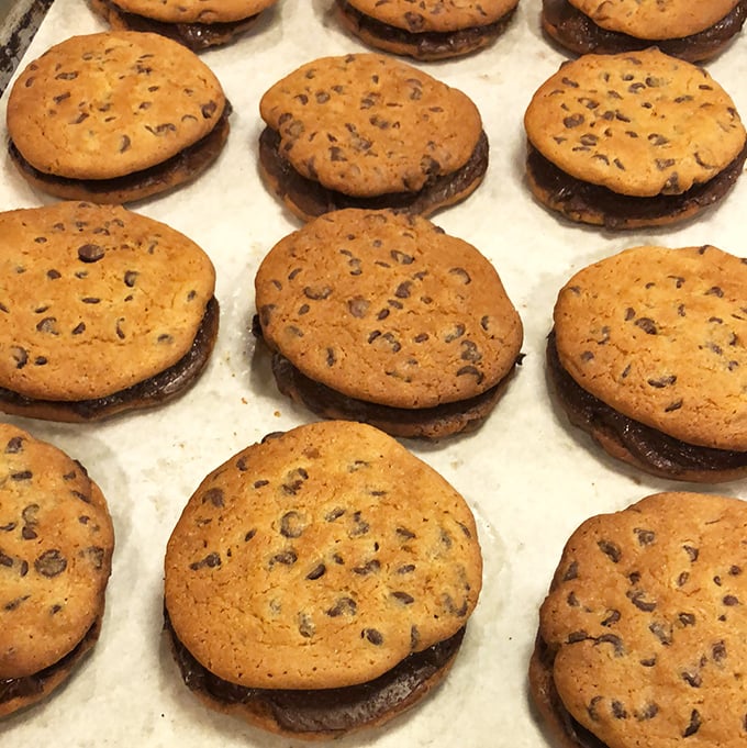Cookie sandwiches that make you question why we ever bothered with regular cookies—chocolate chip perfection bookending what appears to be a life-changing filling.