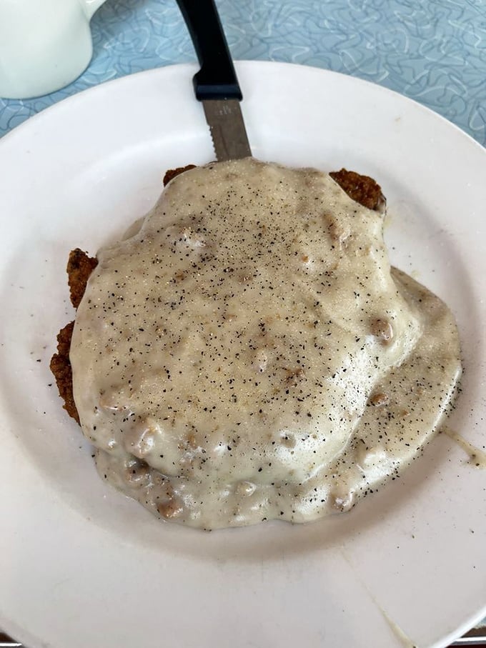 Beneath that blanket of peppery gravy lies a country-fried steak that could convert vegetarians faster than a Chicago winter turns leaves.