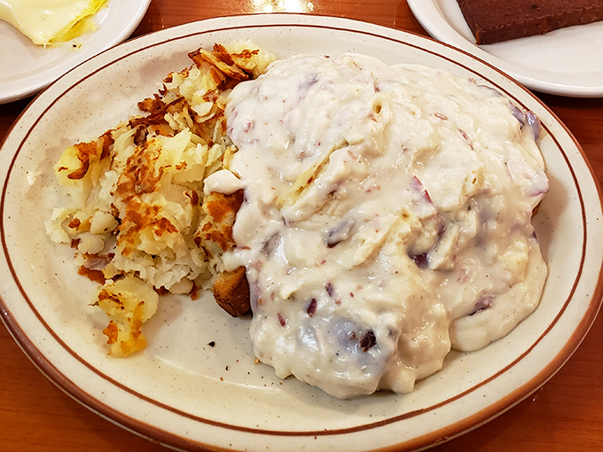 Country fried steak smothered in creamy gravy alongside golden hash browns – the kind of plate that makes you want to hug the cook and take a nap simultaneously.