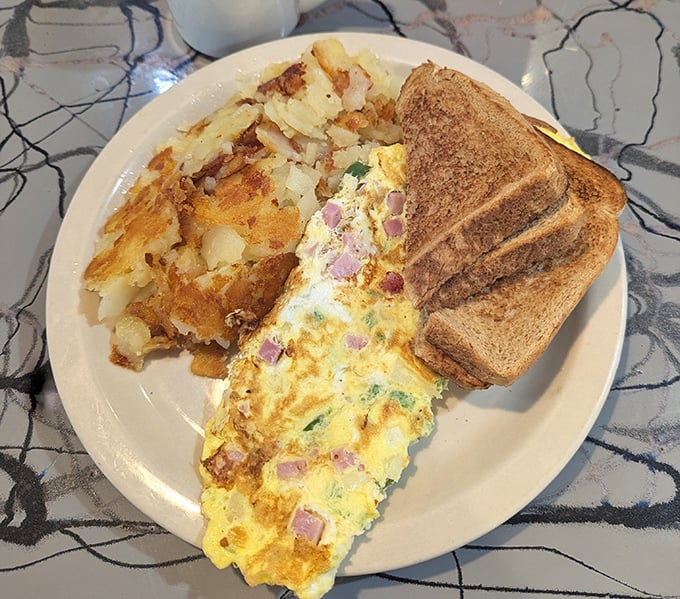This isn't just an omelet – it's a savory morning masterpiece with home fries that crackle with each bite.