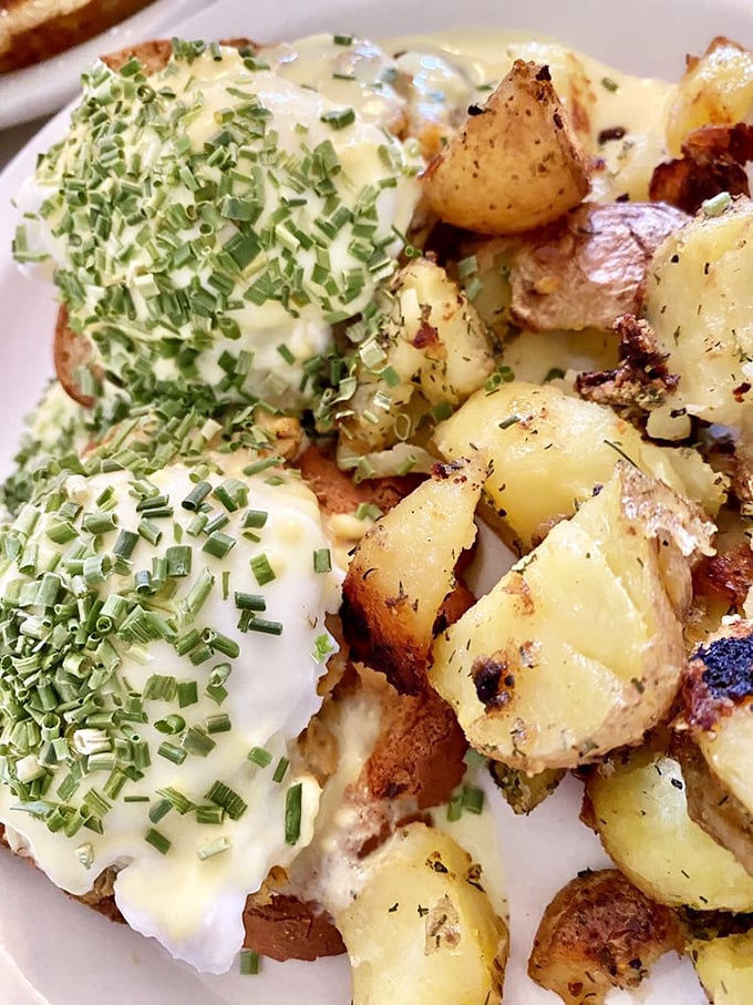 Eggs Benedict gets the royal treatment with perfectly poached eggs draped in hollandaise and sprinkled with fresh chives—breakfast aristocracy at its finest.