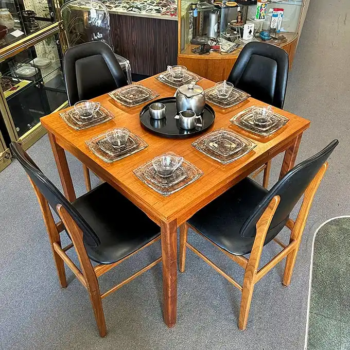 This teak dining set isn't just furniture; it's a time machine to family dinners circa 1965, complete with crystal glassware for your Old Fashioned.