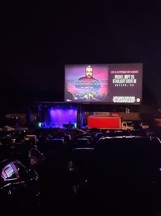 The stage lights up as dusk settles, proving that drive-ins have evolved beyond movies to become community gathering spaces for all entertainment.