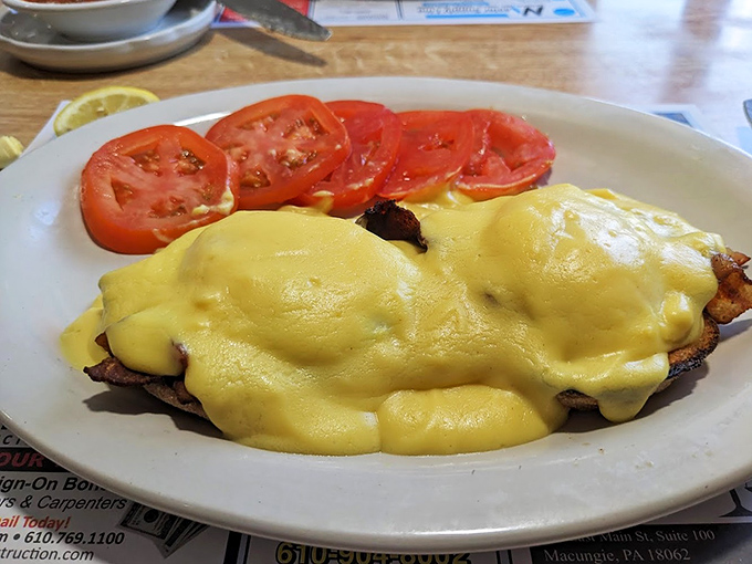 Eggs Benedict with a side of fresh tomatoes – breakfast's answer to formal wear. Hollandaise sauce should be its own food group.