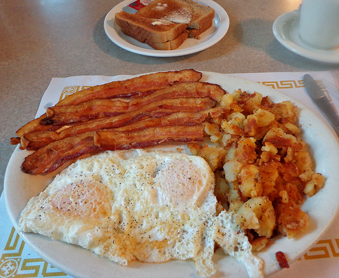 The holy trinity of breakfast: perfectly cooked eggs, bacon with that ideal crisp-to-chewy ratio, and home fries that justify getting out of bed.