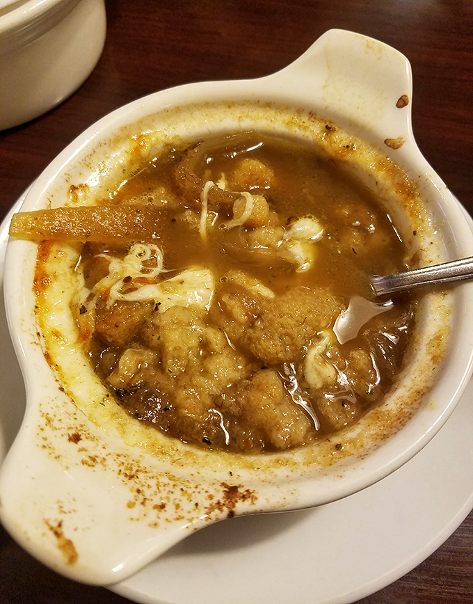 This isn't just soup—it's French onion therapy in a crock, with a golden crown of melted cheese that stretches dramatically with each spoonful.