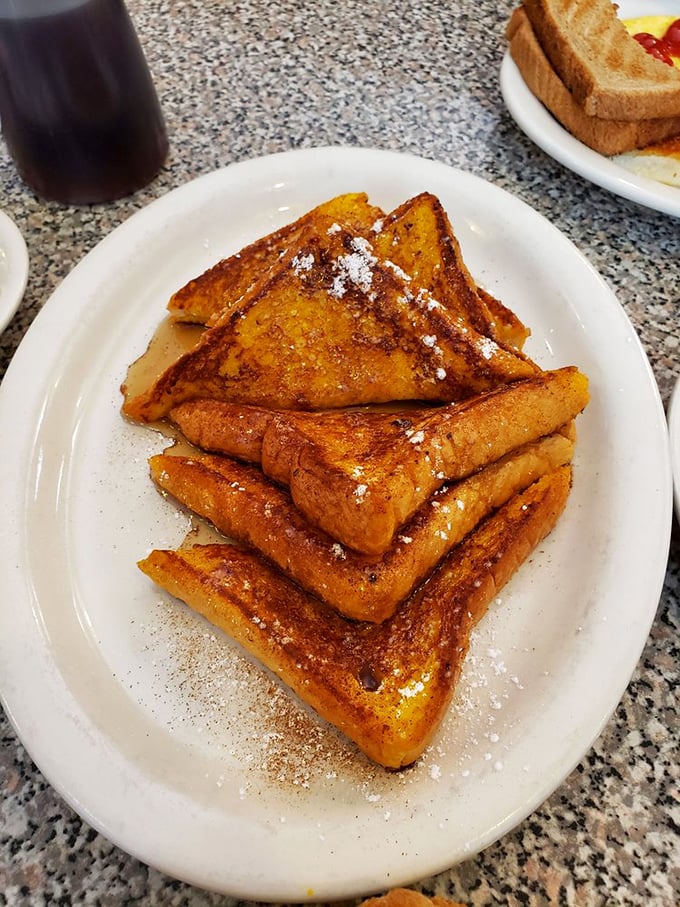 French toast stacked higher than my retirement dreams, dusted with powdered sugar like the first perfect snowfall of winter.