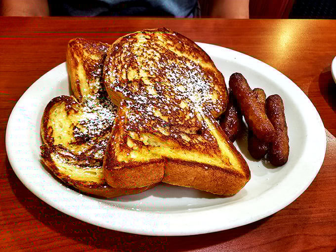 French toast that makes ordinary bread feel special—dusted with powdered sugar like the first perfect snowfall of winter. Those sausages aren't just along for the ride.