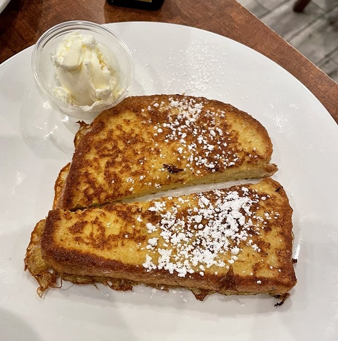 The legendary French toast – golden-brown perfection dusted with powdered sugar, waiting for that first magical bite that justifies setting your alarm.