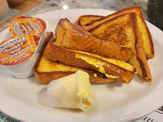 French toast stacked higher than your weekend expectations, golden-brown and ready for its maple syrup waterfall moment.