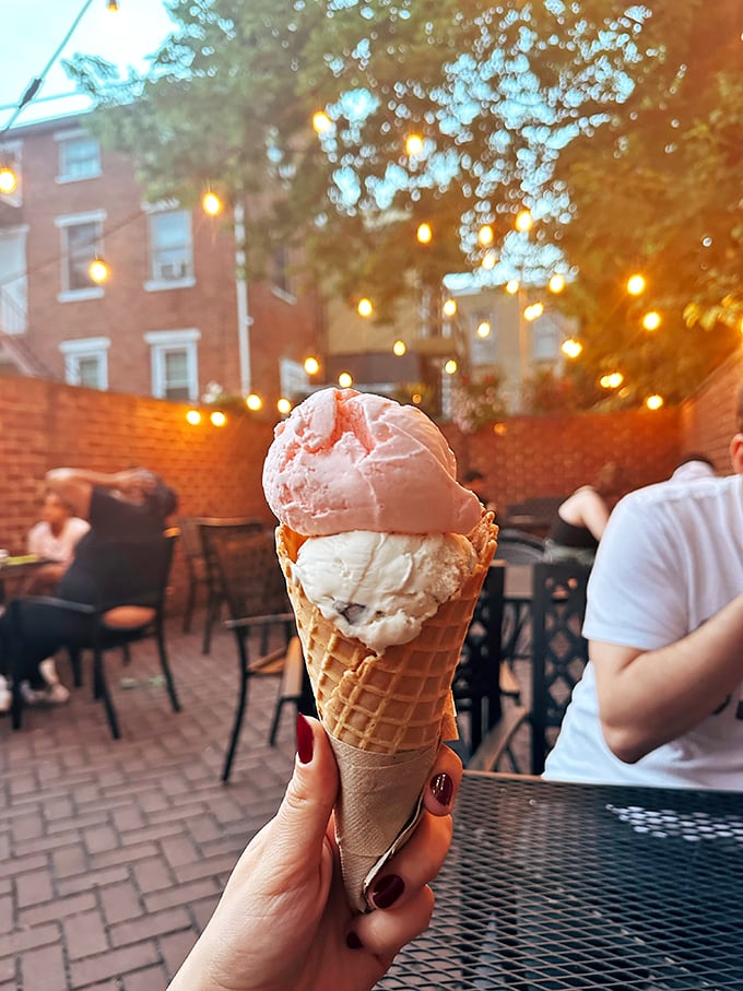 Twilight magic in Lancaster: two perfect scoops nestled in a waffle cone, framed by string lights and brick walls.
