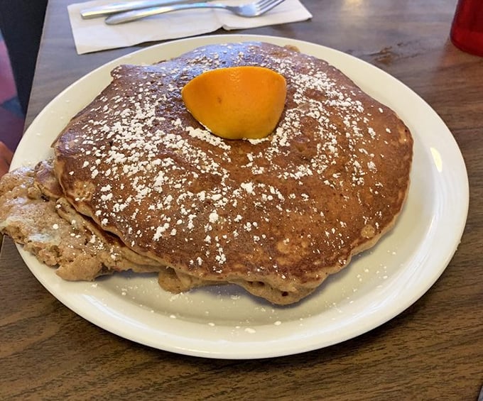 The griddle cake that launched a thousand food pilgrimages—wider than the plate, dusted with powdered sugar, and crowned with a pat of butter.