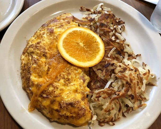 This omelet has more cheese than my uncle's jokes at Thanksgiving dinner. The orange slice isn't just garnish—it's a vitamin C life raft in a sea of delicious indulgence.