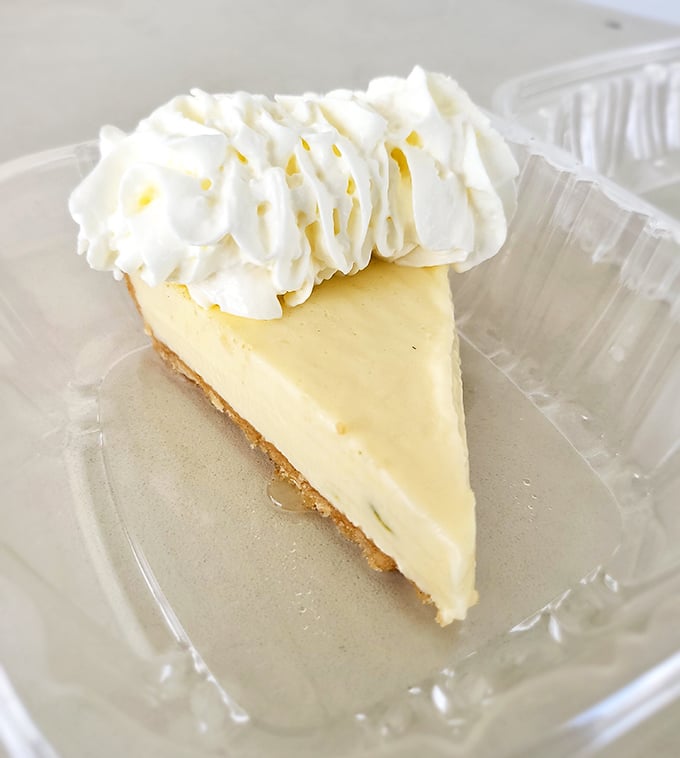 The key lime pie reveals its true colors—pale yellow, not green—with a cloud of whipped cream that makes this slice of heaven even more heavenly.