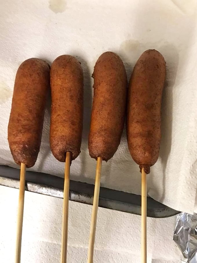 Carnival food that demands both napkins and devotion—these corn dogs represent the universal truth that anything on a stick tastes better at a flea market.