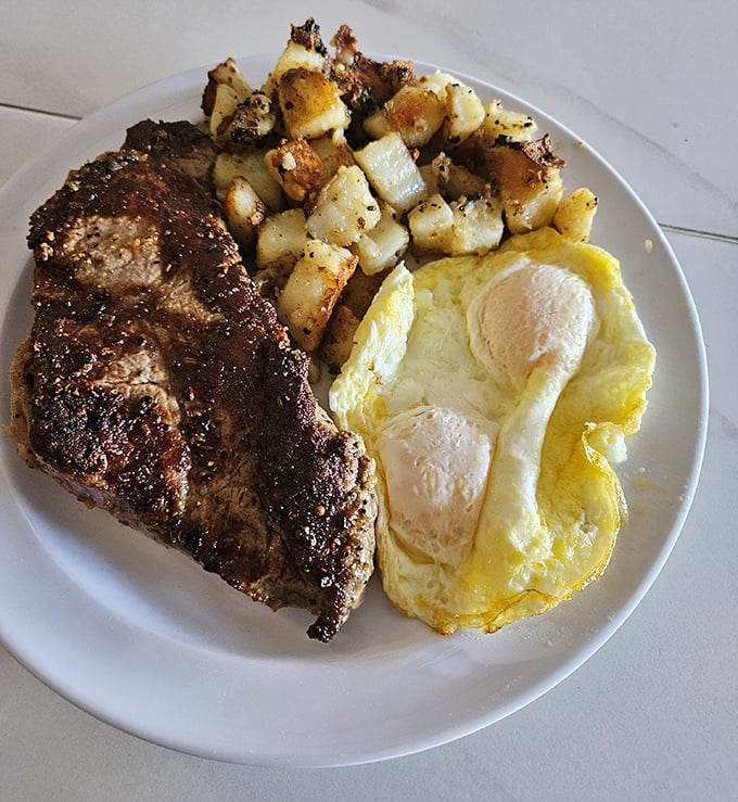 A New York steak cooked exactly how you want it, alongside eggs and home fries—proof that sometimes the simplest combinations are the most satisfying.