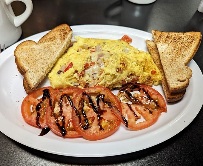 An omelet that's seen things—stuffed with savory fillings and paired with perfectly arranged tomato slices drizzled with balsamic artistry.