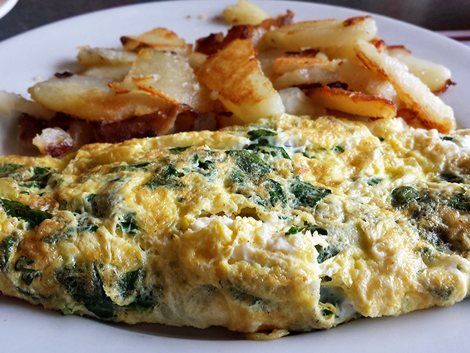 The spinach omelet that launched a thousand brunches – fluffy eggs folded around vibrant greens, paired with home fries that achieve the perfect crisp-tender balance.