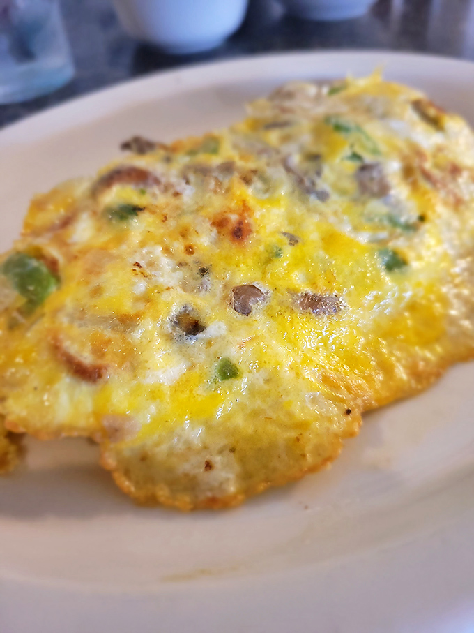 An omelet that doesn't just contain vegetables—it celebrates them under a golden canopy of perfectly cooked eggs and melted cheese.