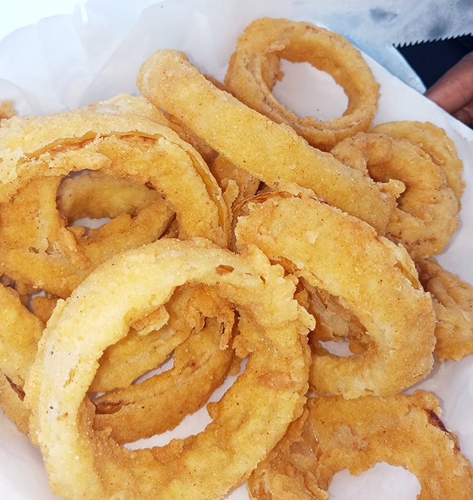 These aren't just onion rings – they're golden halos of happiness. The kind of crispy perfection that makes you forget you're technically eating a vegetable.