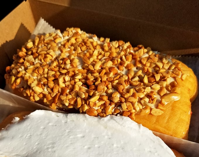 A peanut butter long john that doesn't just sit on the plate—it commands attention with its generous nutty crown.