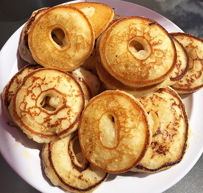 These aren't just pancakes; they're golden discs of happiness with perfect little holes designed by breakfast engineers to capture syrup.