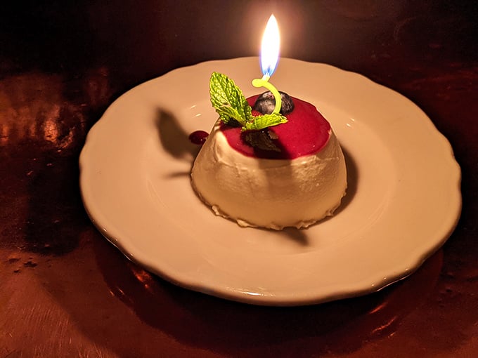 A panna cotta with berry topping and a birthday candle—dessert that says "celebration" without shouting it from the rooftops.