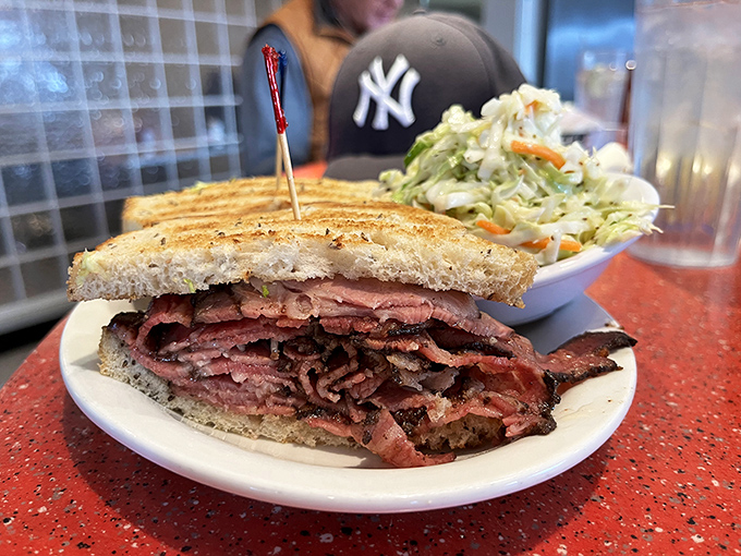 This isn't just a sandwich; it's a skyscraper of pastrami that requires strategic planning, a good jaw hinge, and absolutely zero first-date nerves.