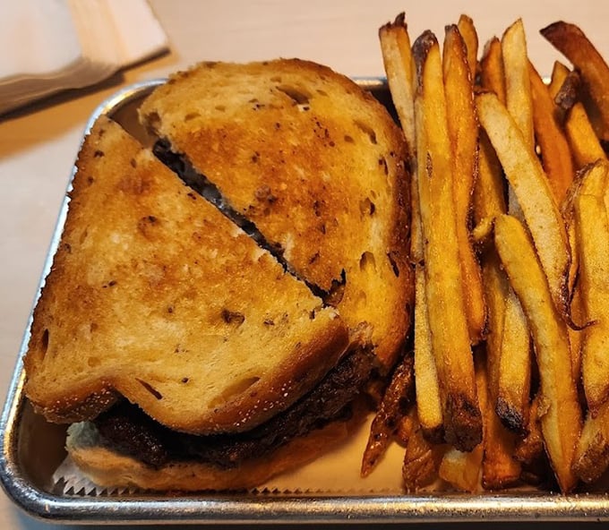 The patty melt—that brilliant marriage of burger and grilled cheese—served with fries that deserve their own fan club.