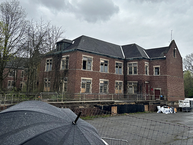 Rain-slicked grounds and ominous clouds provide the perfect backdrop for this imposing structure that seems to watch visitors approach.