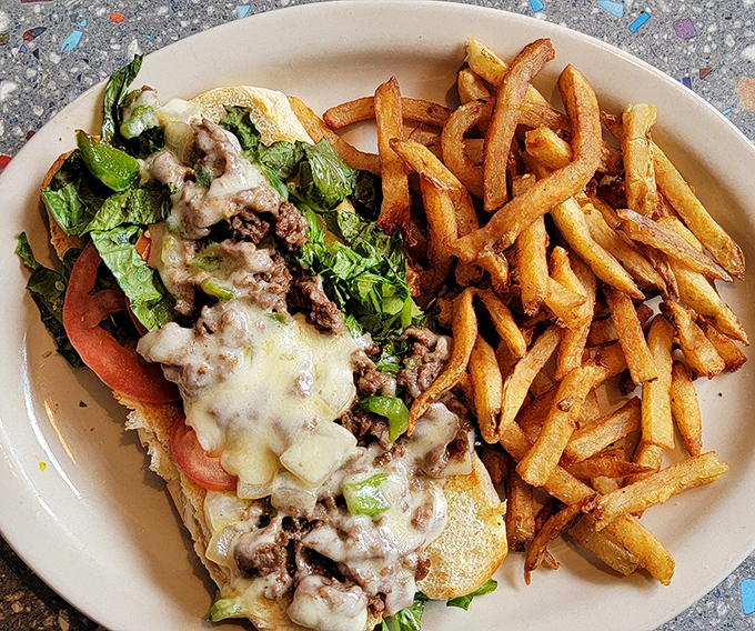 The legendary Philly cheesesteak in all its glory—tender beef, melted cheese, and fresh veggies served alongside golden fries that demand to be stolen.